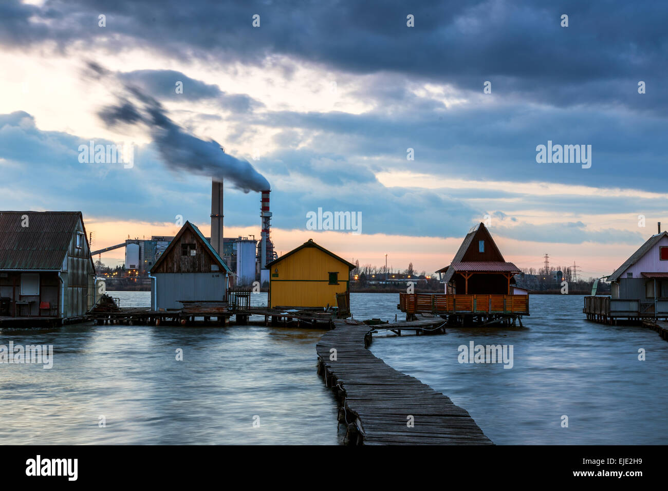 Sunset lake Bokod with pier and fishing wooden cottages, power plant in ...