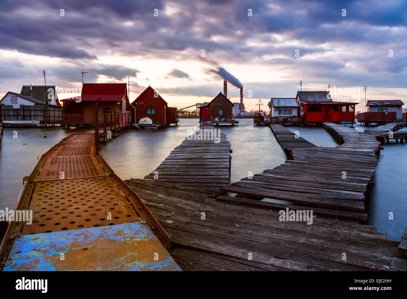 Sunset lake Bokod with pier and fishing wooden cottages, power plant in ...
