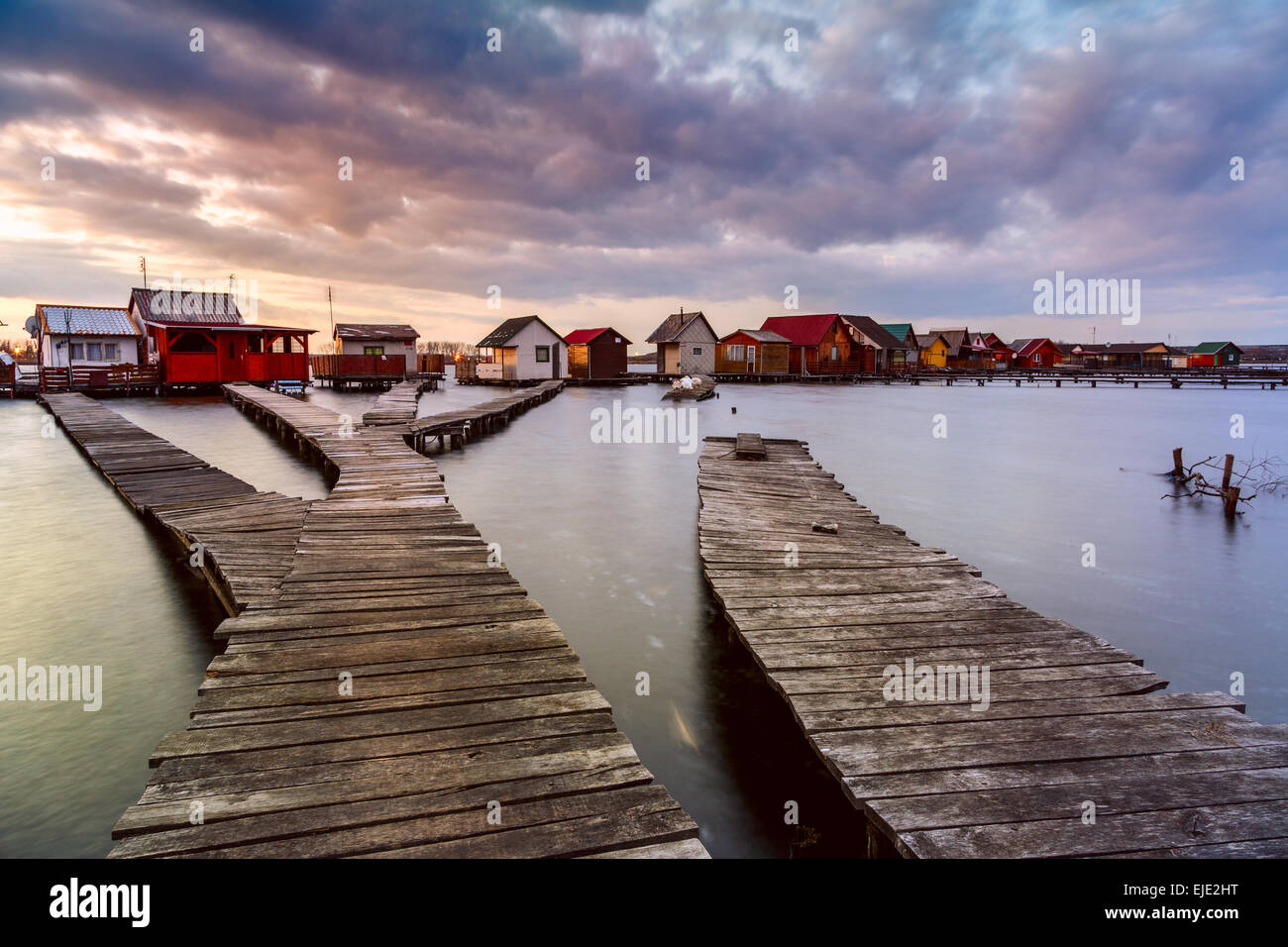 Sunset lake Bokod with pier and fishing wooden cottages, power plant in ...