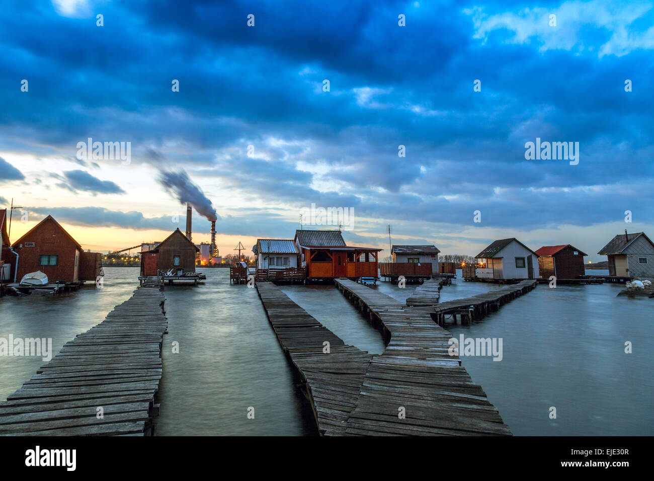 Sunset lake Bokod with pier and fishing wooden cottages, power plant in ...