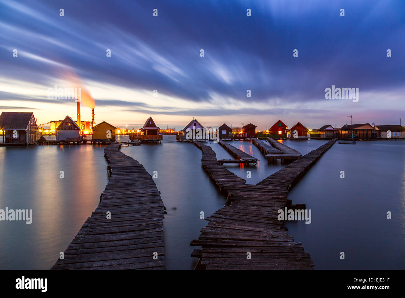 Sunset lake Bokod with pier and fishing wooden cottages, power plant in ...