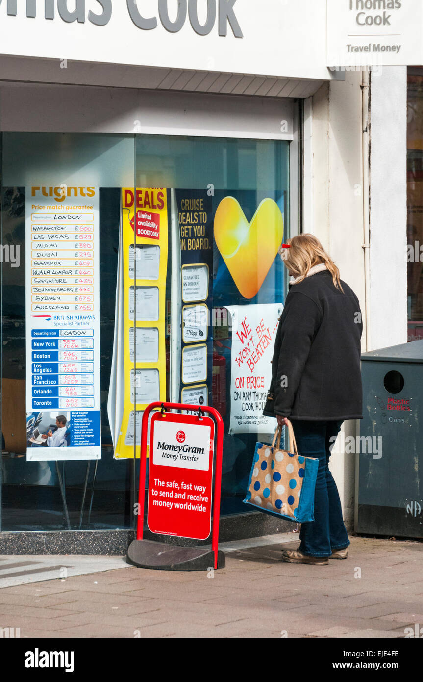 Woman looking at offers in the window of a Thomas Cook travel agents ...