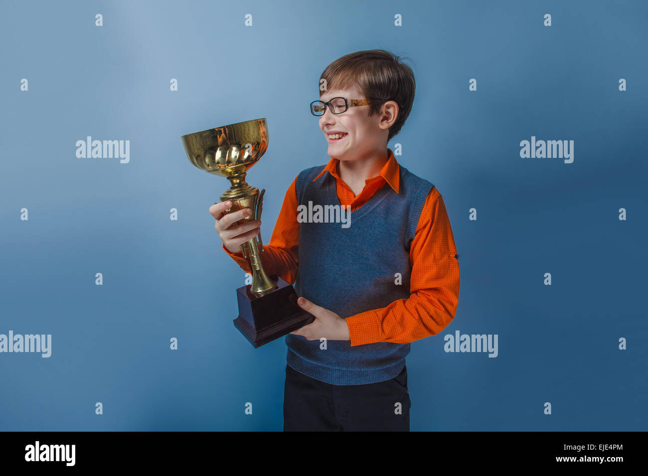 European-looking boy of ten years in glasses holding a cup award on a ...