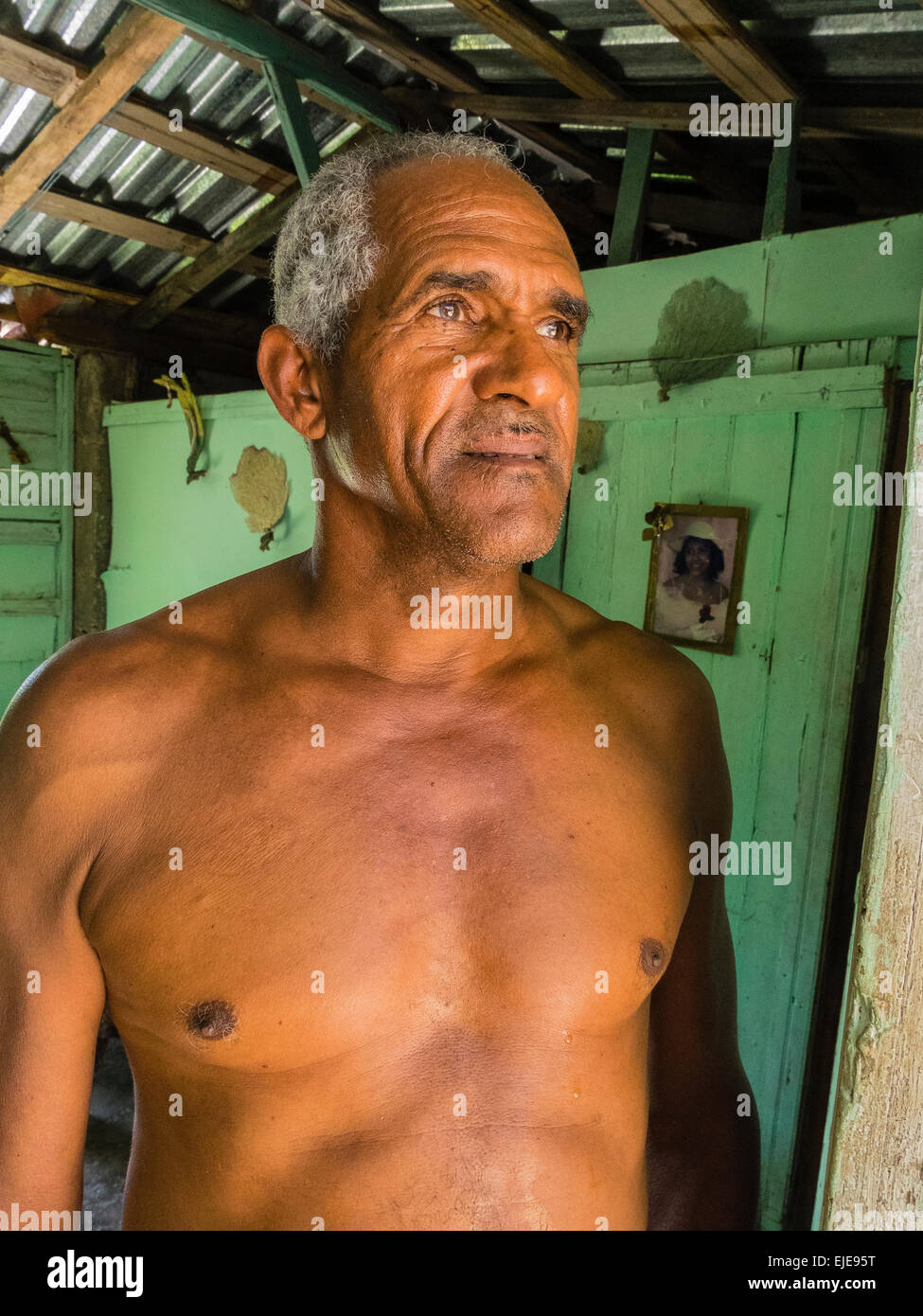 An Afro-Cuban man without a shirt stands in the doorway of his modest ...