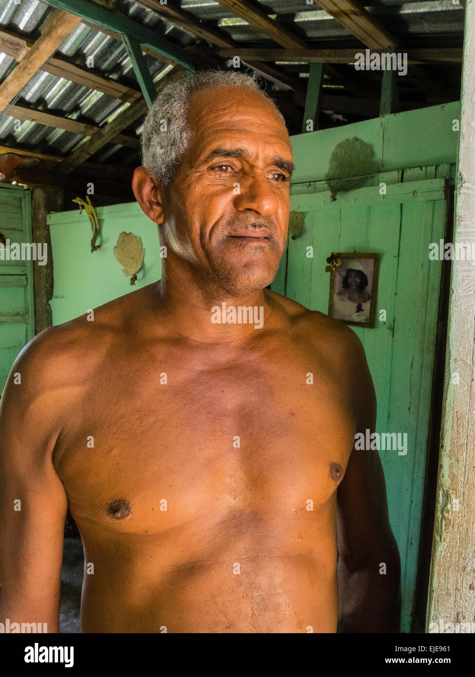An Afro-Cuban man without a shirt stands in the doorway of his modest ...