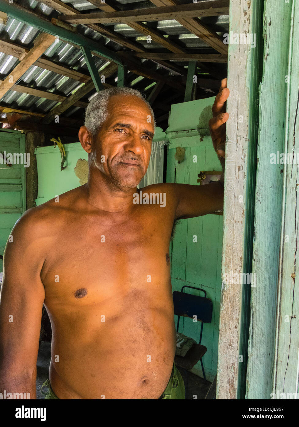An Afro-Cuban man without a shirt stands in the doorway of his modest ...