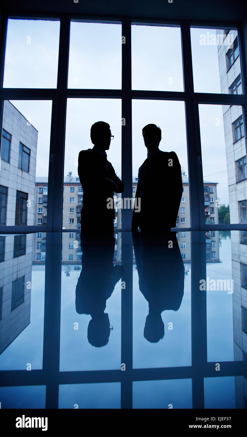 Two businessmen talking by the window in office Stock Photo - Alamy