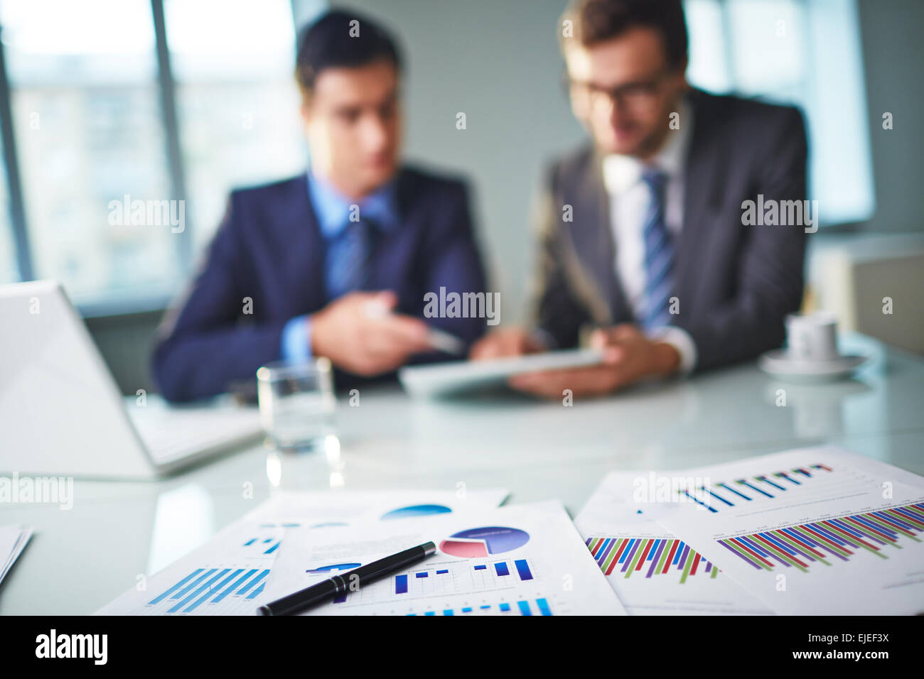 Business documents at workplace and two businessmen networking on ...