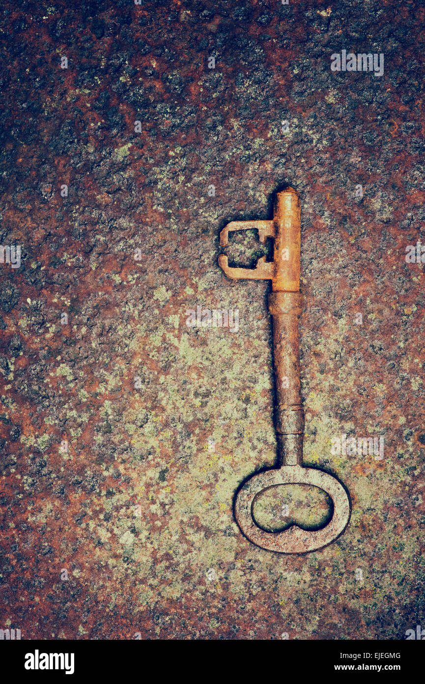 Old key on a rusty metal texture background with applied vintage filter ...