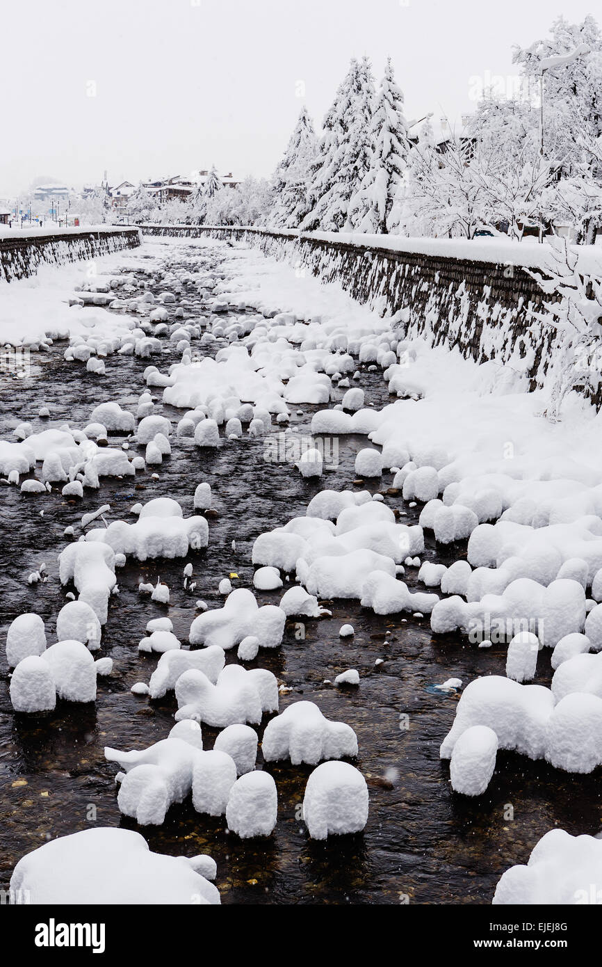 Snow caps on boulders in the mountain river formed after heavy snowfall ...
