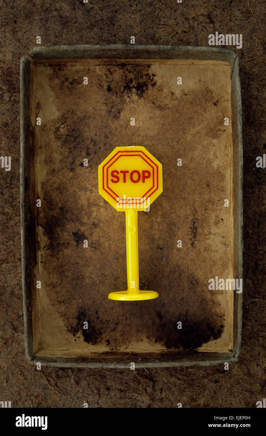 Plastic model of yellow roadsign stating Stop and lying in stained card ...