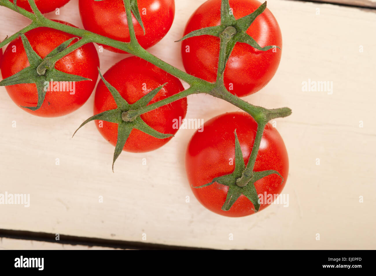fresh cherry tomatoes on a cluster over rustic wood table Stock Photo ...