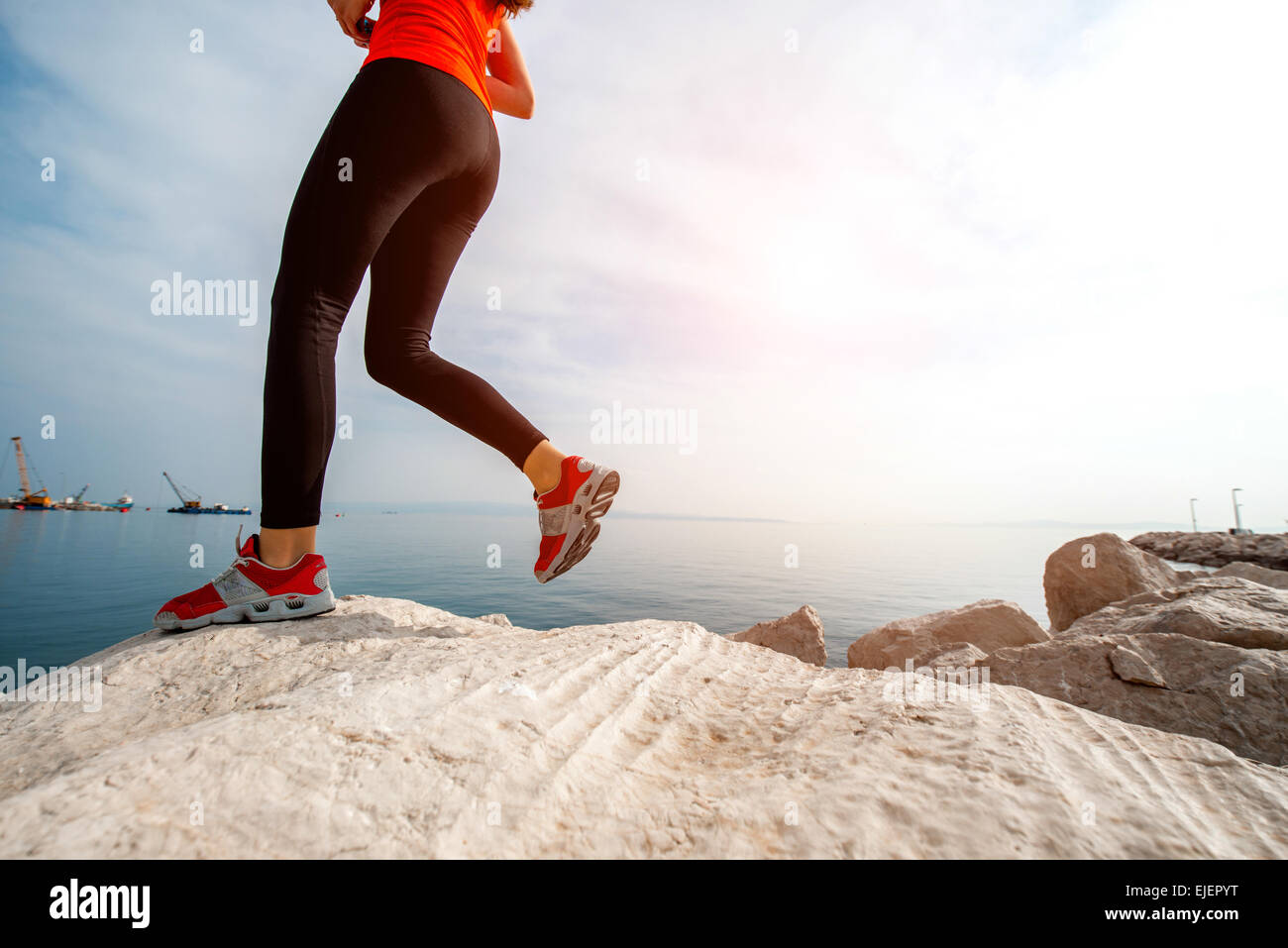 Woman running on beach rocks hi-res stock photography and images - Alamy