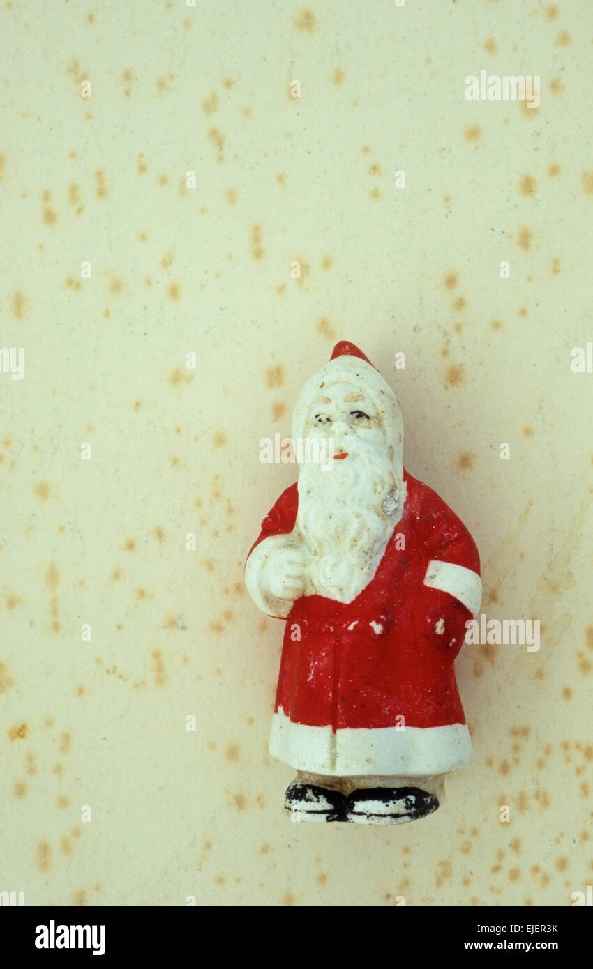 Well worn vintage plaster Father Christmas model standing against foxed ...