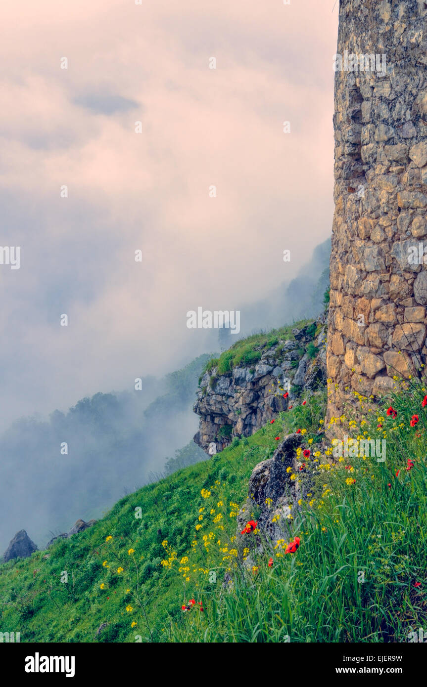 Tower stone wall above mist on green landscape of mountainous Karabakh ...
