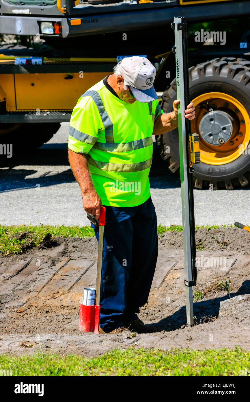 Highway maintenance worker using a digital depth guage as the backhoe ...
