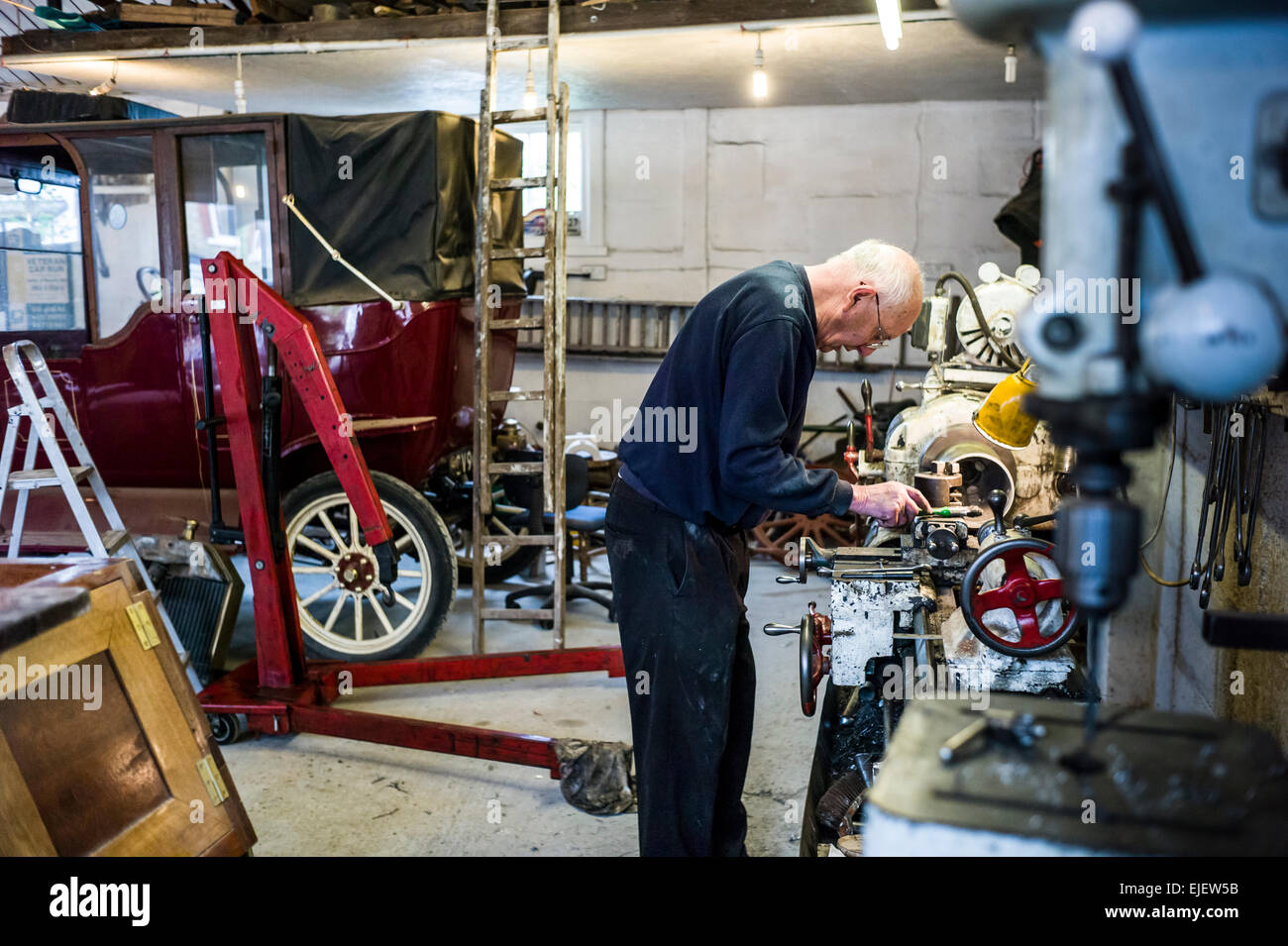 Engineer and vintage car maker working on his lathe in the workshop ...