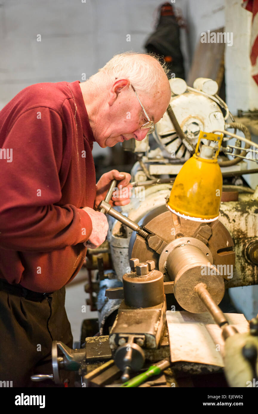 Engineer and vintage car maker working on his lathe in the workshop ...