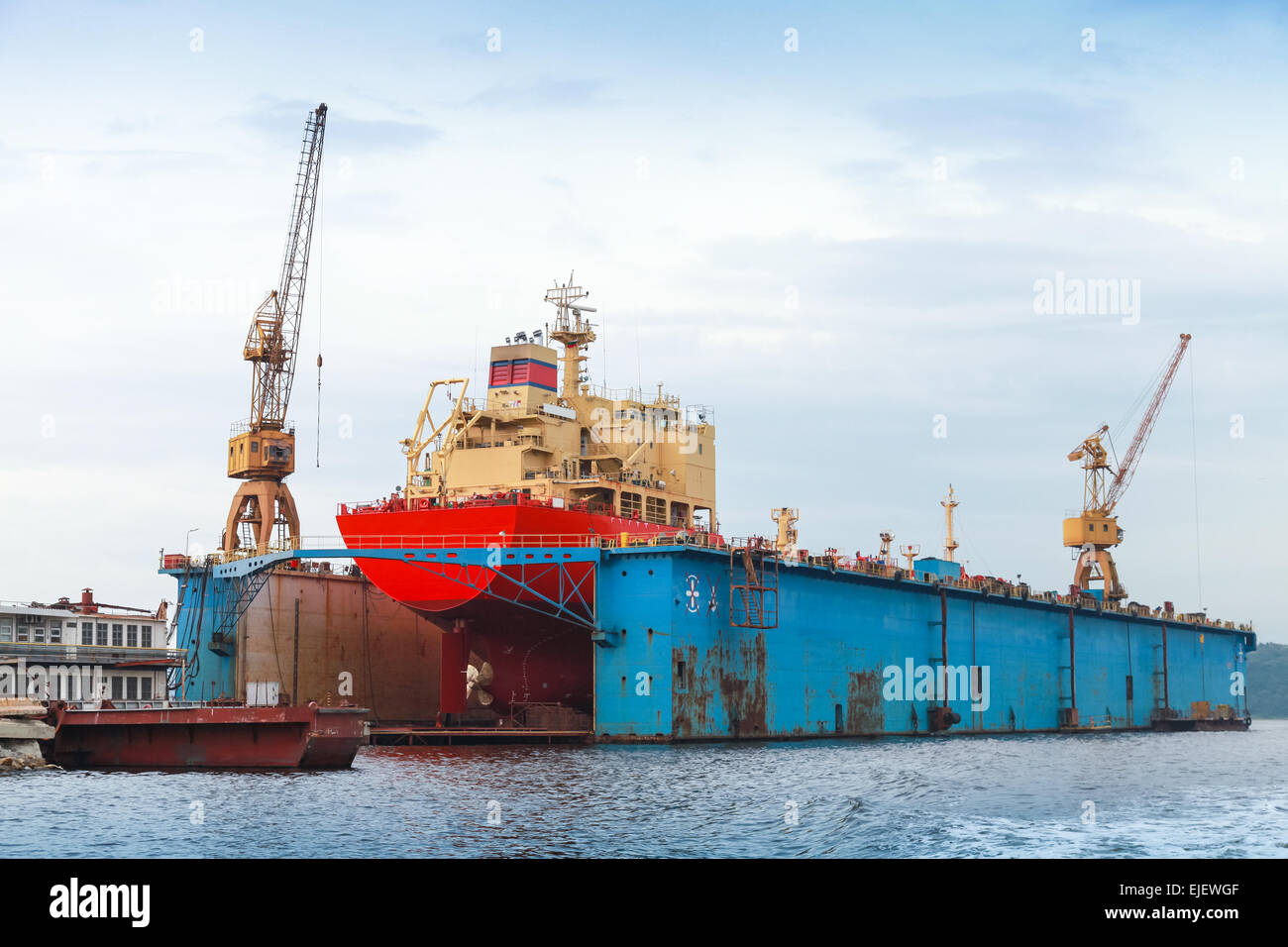 Floating blue dry dock with red tanker under repair inside, back view ...