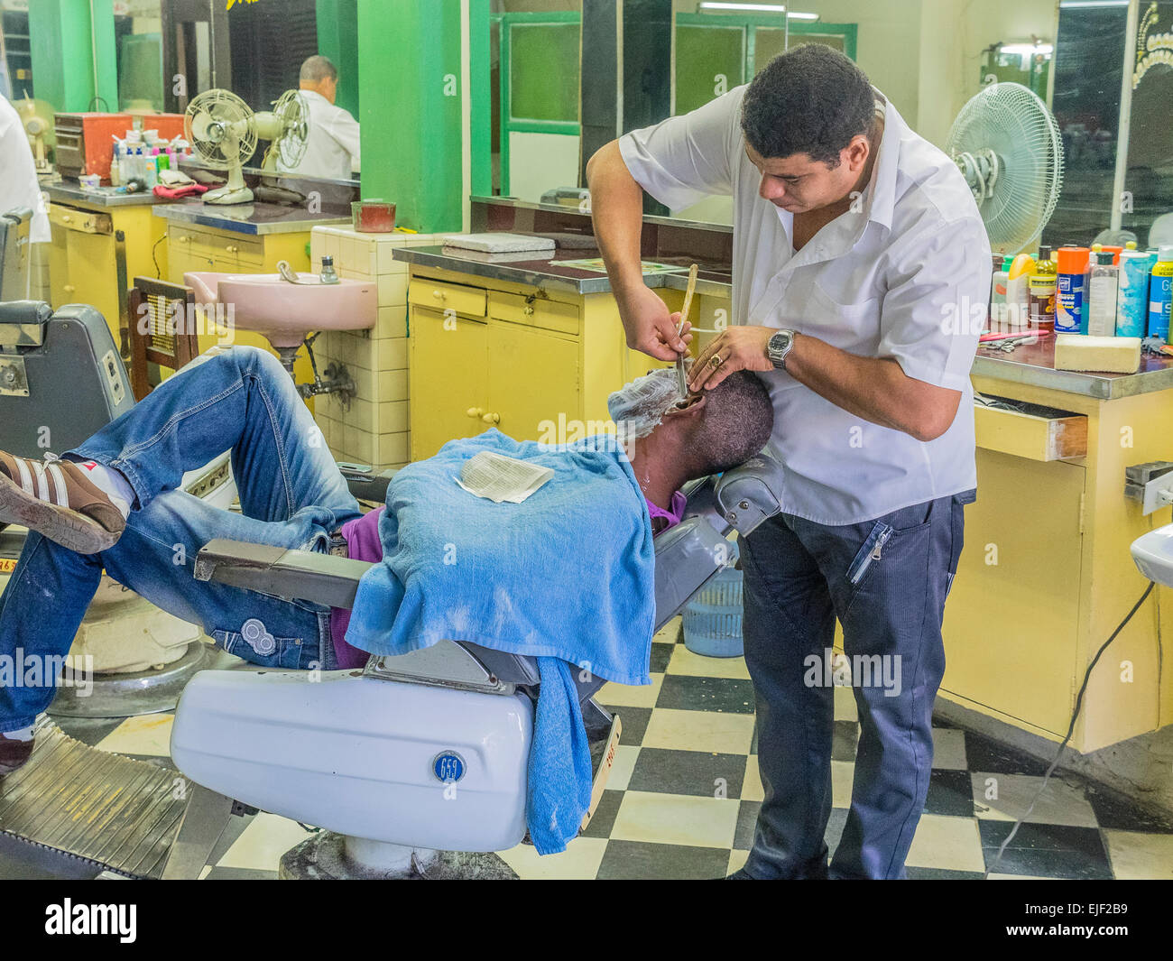 Cuban man lies down in the barber's chair and gets shave in barber shop ...