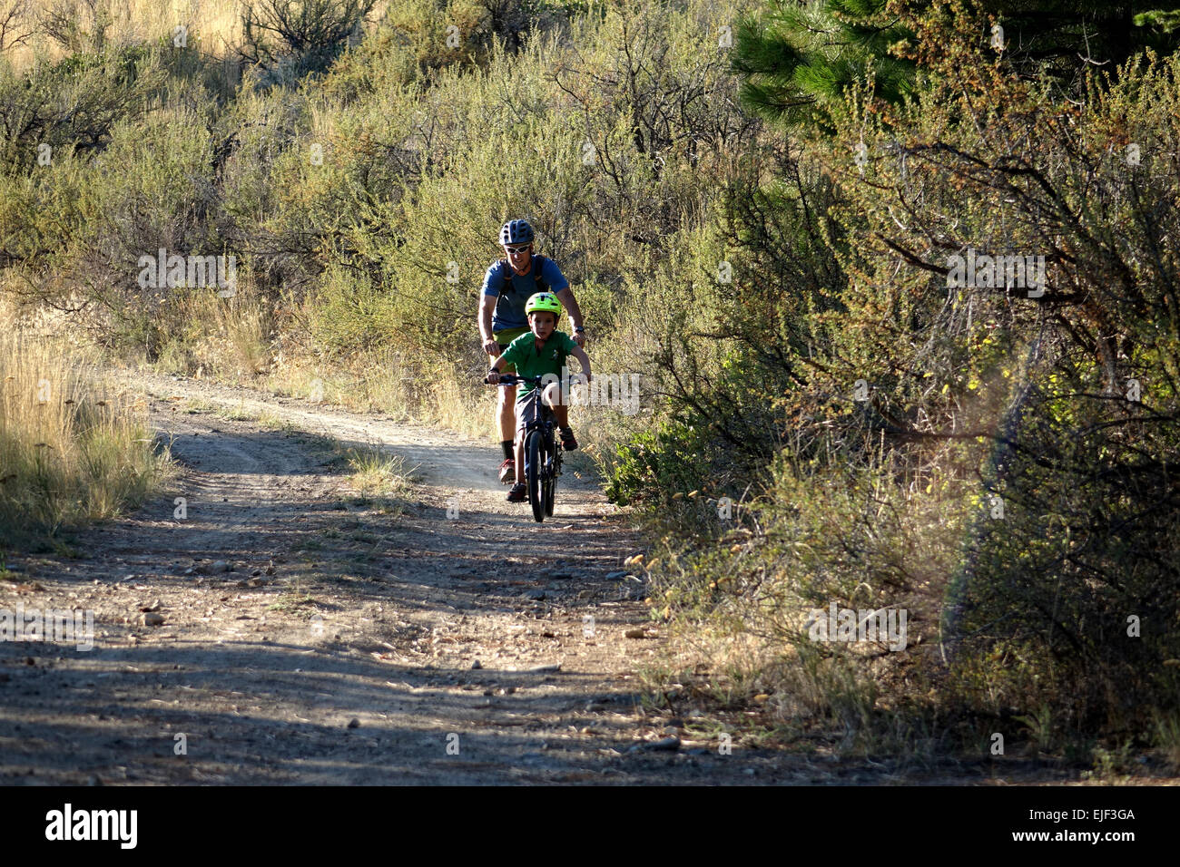 A father follows his son down a dirt dual track trail at Echo Ridge ...