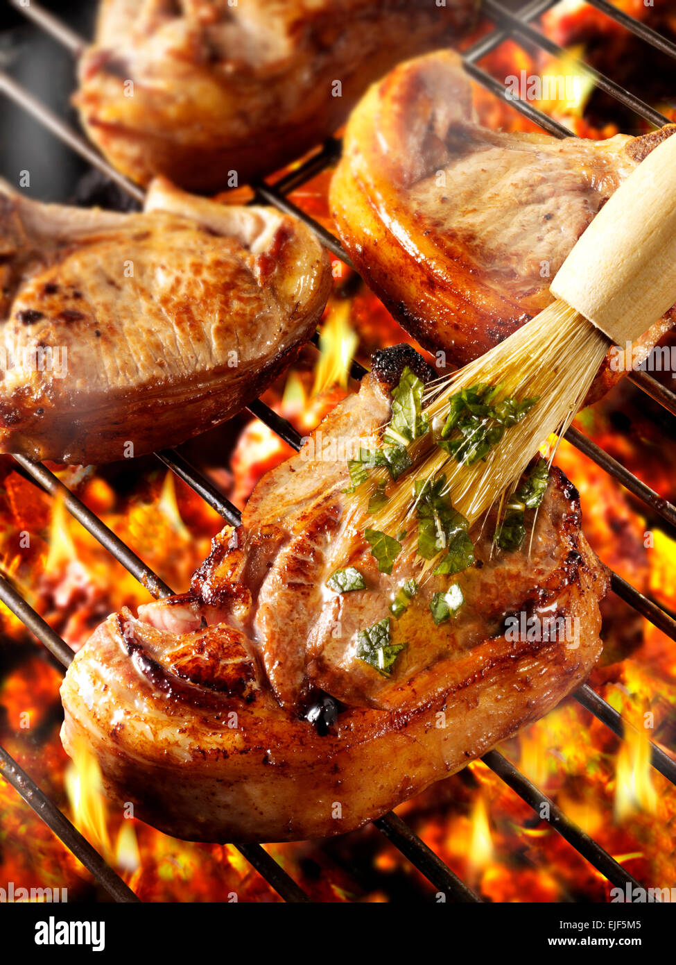 Cooking on a BBQ with hot coals and lamb cutlets being marinated with ...