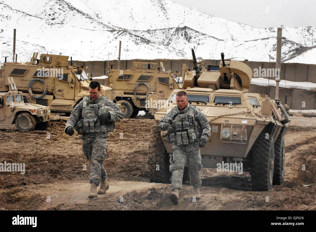 Two U.S. Army soldiers walk their vehicle through the muddy paths of ...