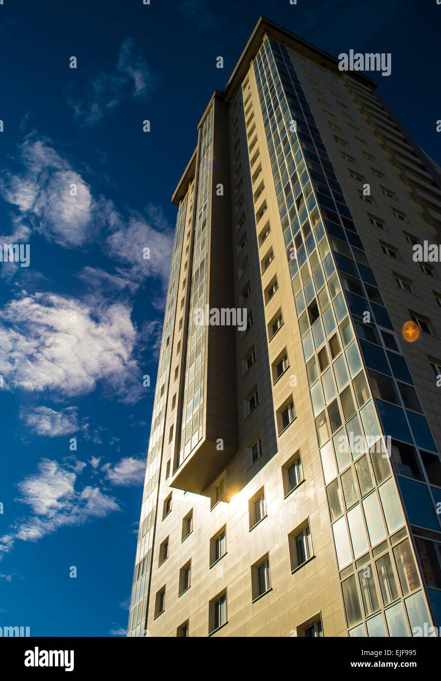 A Modern high rise apartment block stretches into the blue white cloud ...