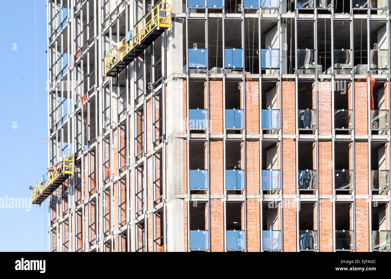 A high rise office building under construction with workers working on ...