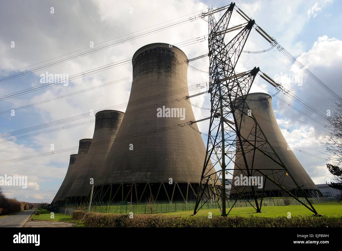 Cooling towers and electricity pylons against a bright cloudy sky at ...