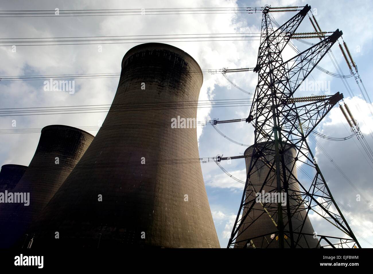 Cooling towers and electricity pylons against a bright cloudy sky at ...