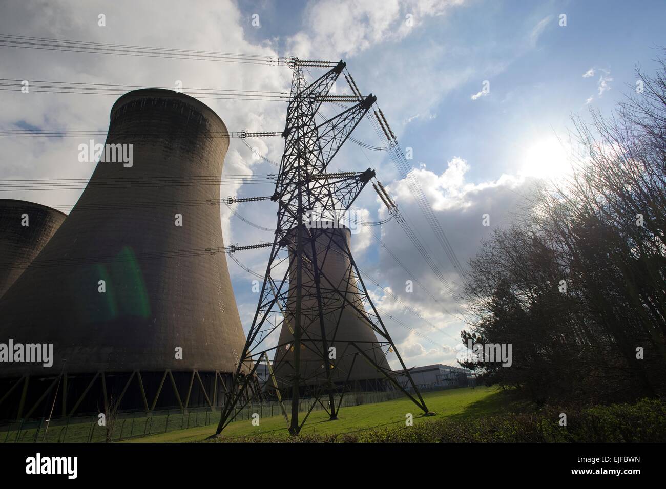 Cooling towers and electricity pylons against a bright cloudy sky at ...