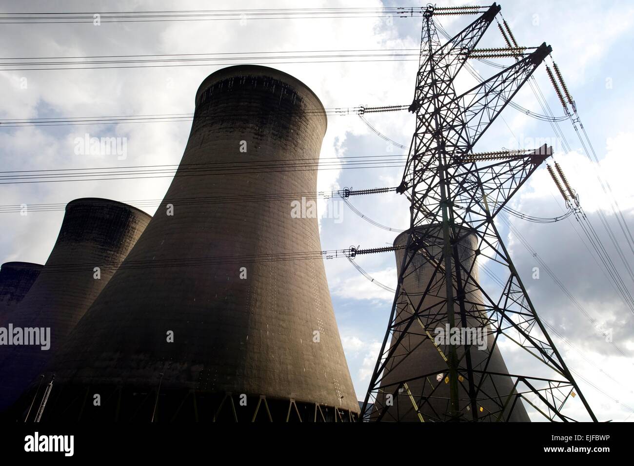 Cooling towers and electricity pylons against a bright cloudy sky at ...