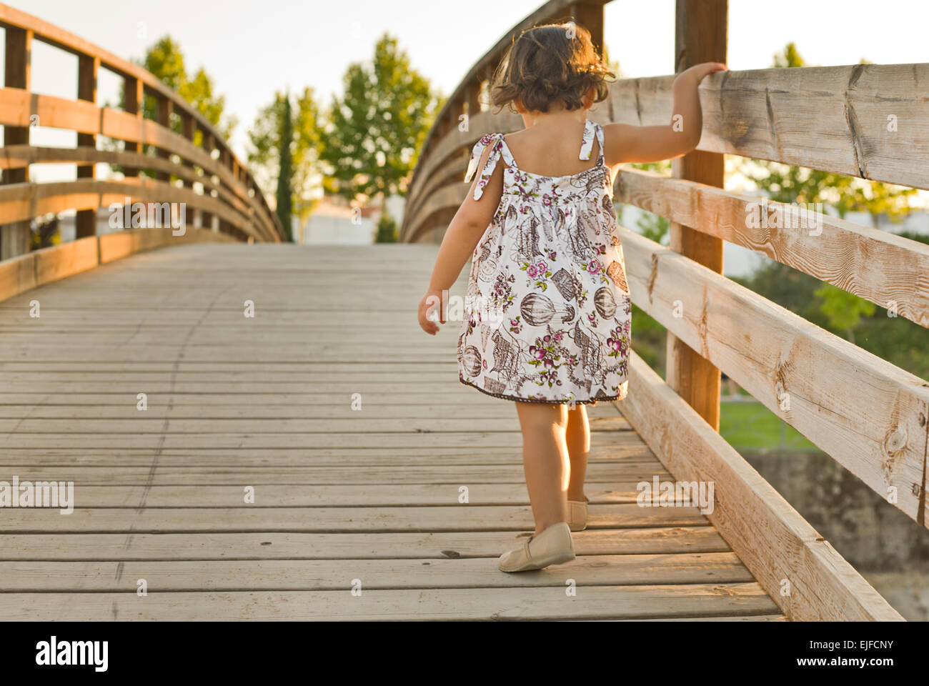 Little baby girl crossing a wooden bridge. Rear view Stock Photo - Alamy
