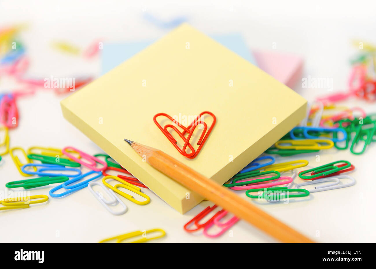 Small note pad and a pencil on a background of multi-colored paper ...