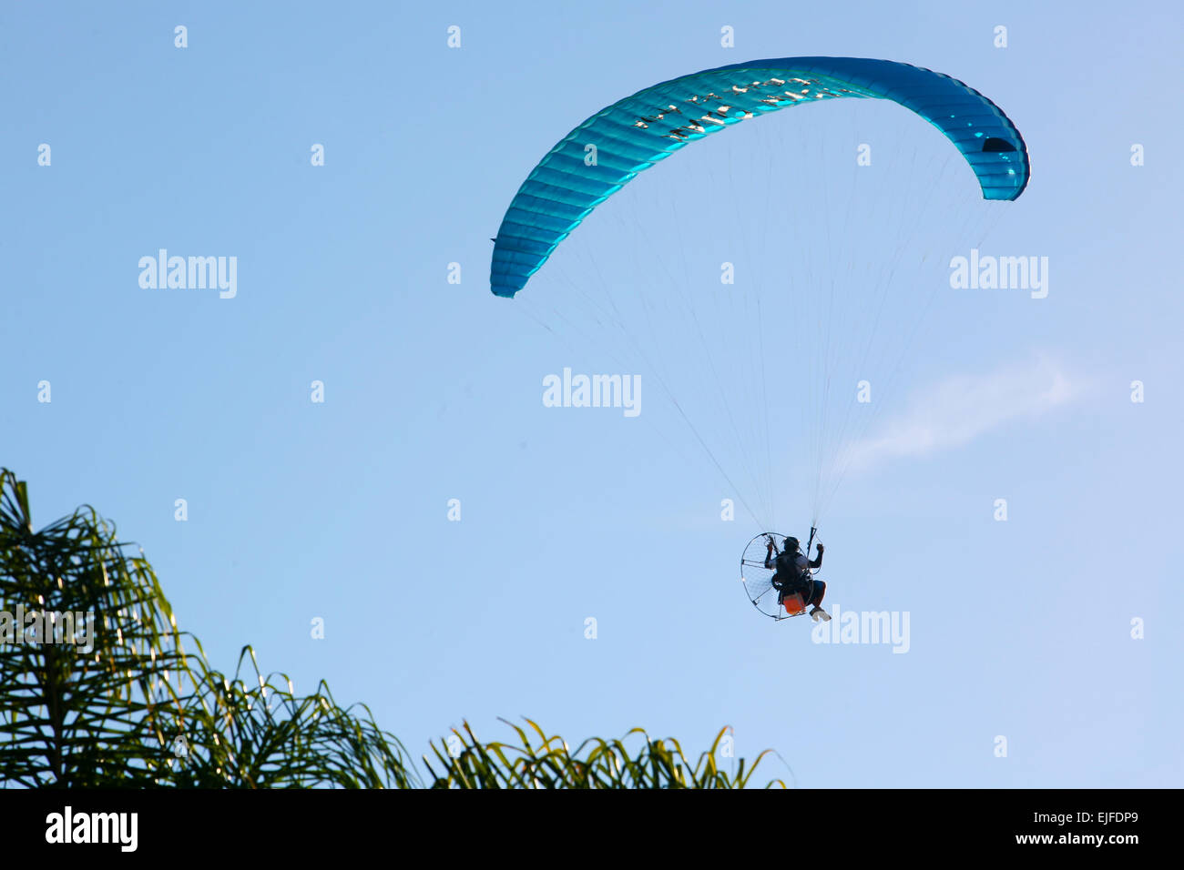 A powered paraglider pilot in flight with a blue clean sky in the ...
