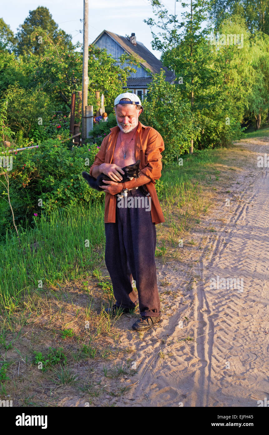 Rural landscape - man and black cat on sandy road in village Stock ...