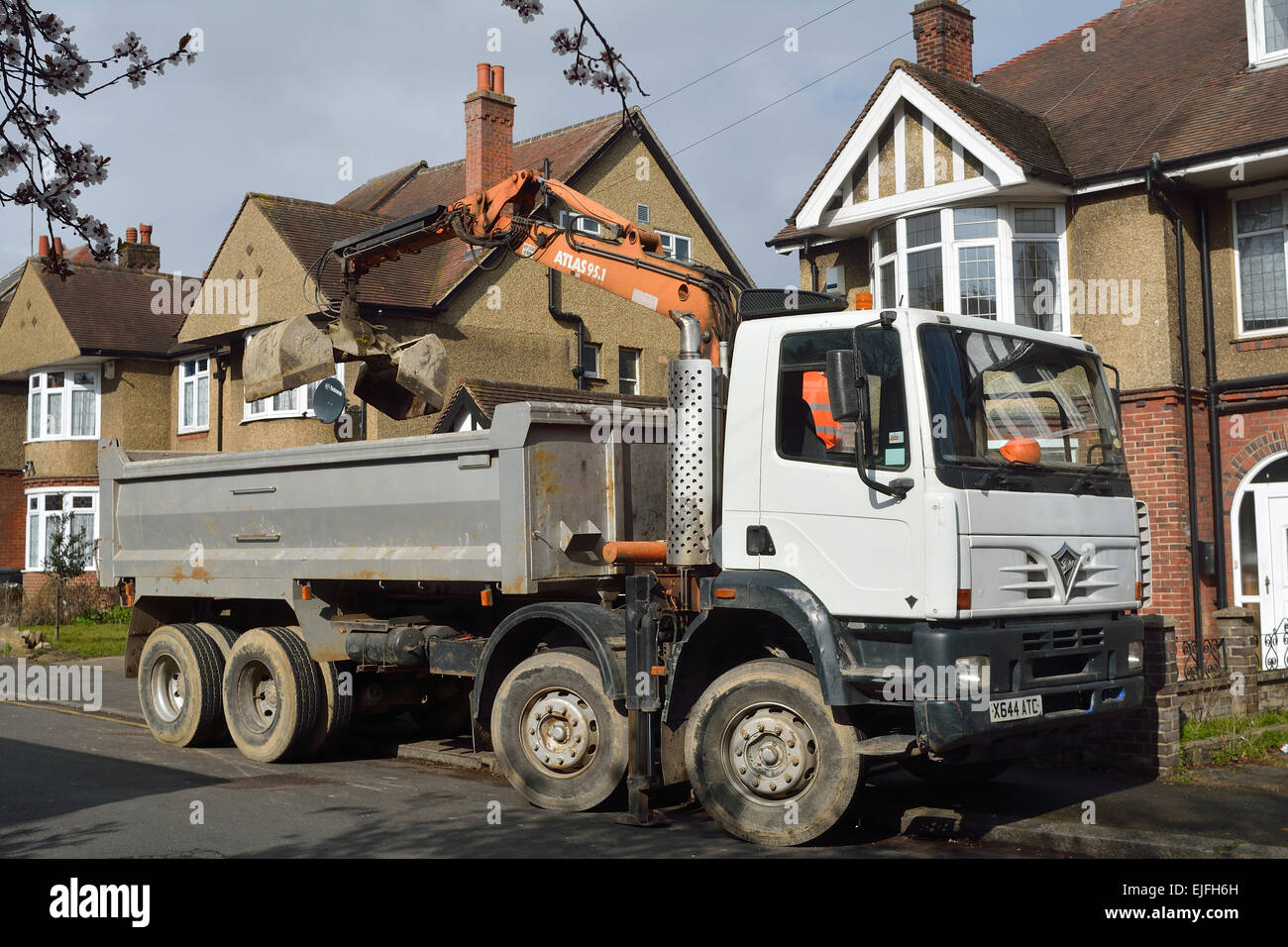 Dumper truck with hydraulic scoop bucket in use on a residential street ...