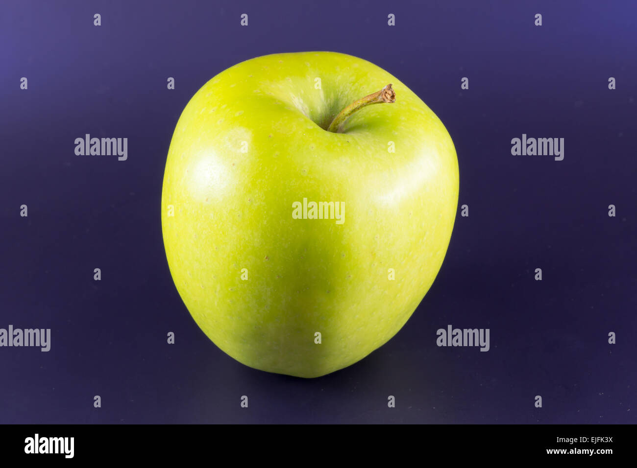 A single golden yellow apple fruit on blue isolated background Stock ...