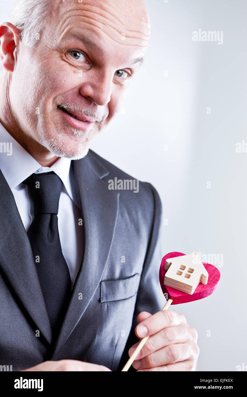real estate salesman showing off a little house in a heart-shaped ...