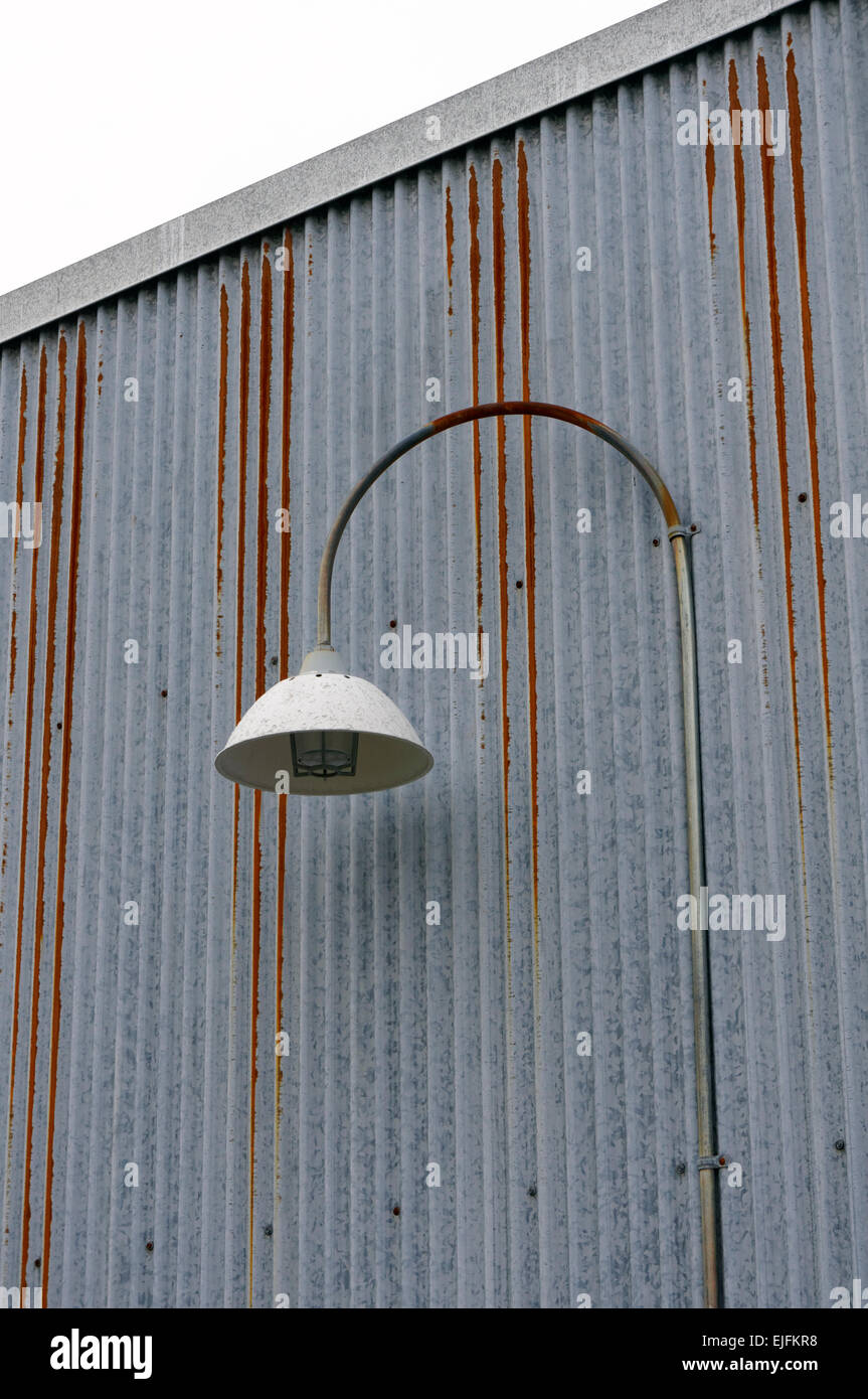 Curved metal street lamp attached to the corrugated metal wall of a ...