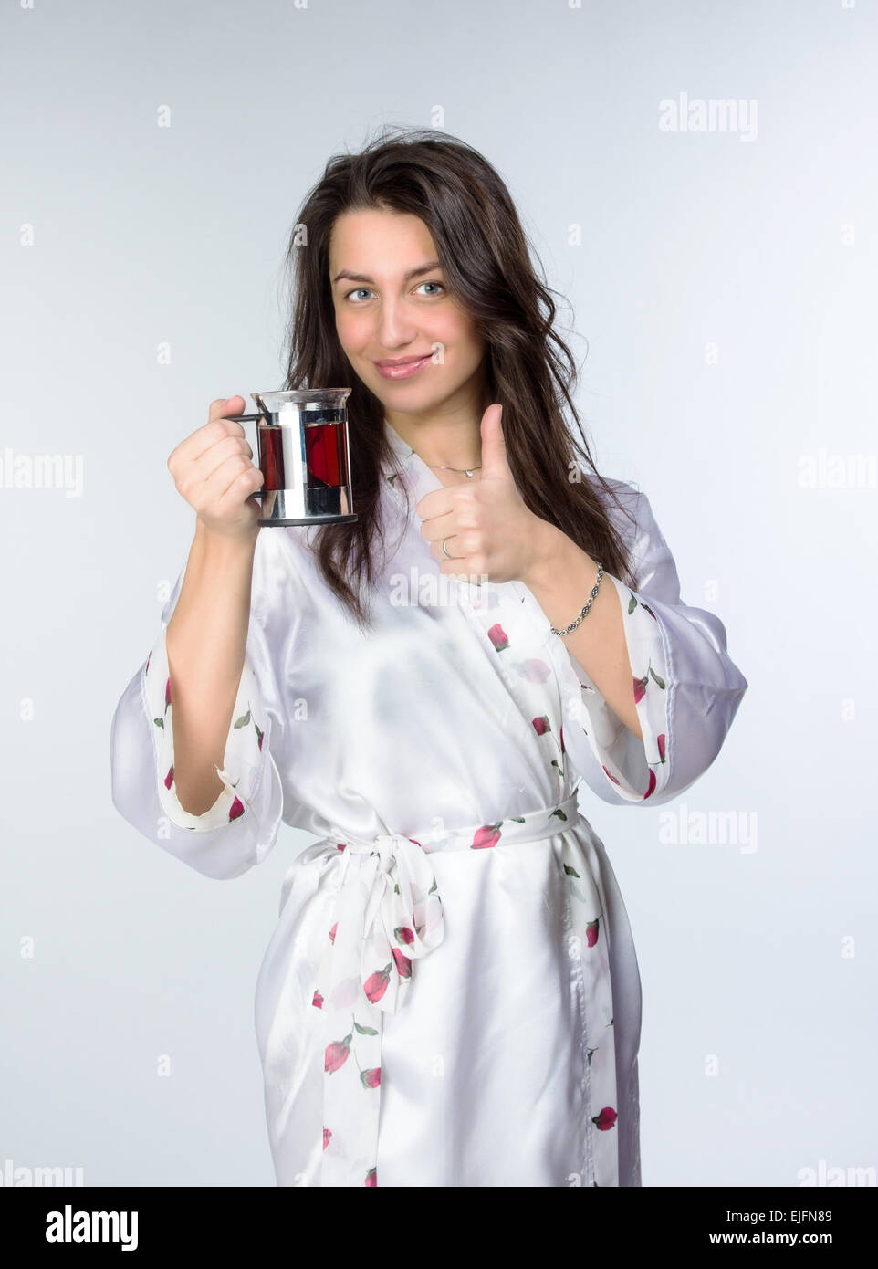 Happy young woman enjoys drinking her coffee and showing thumbs up on ...