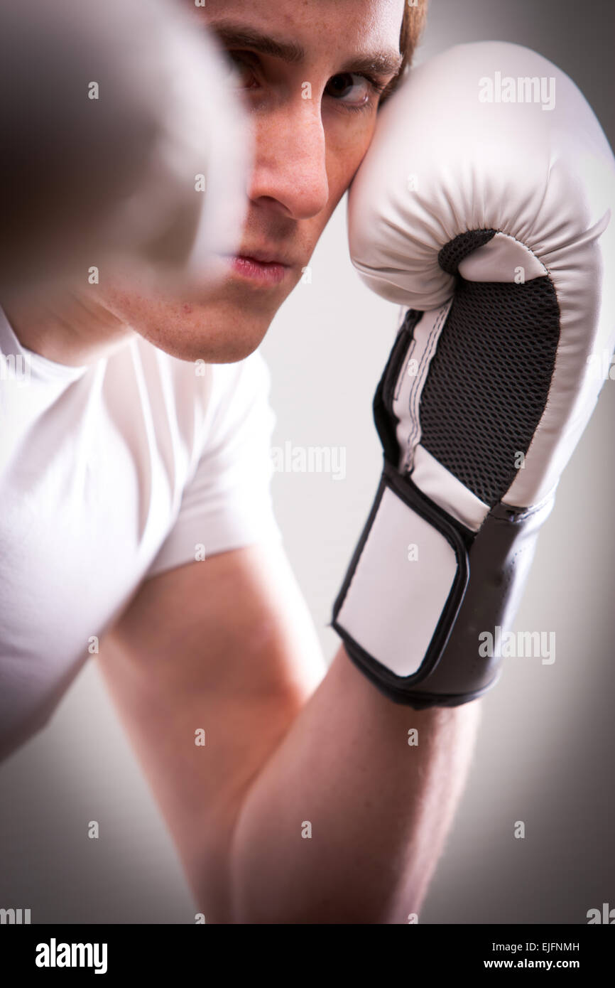 young powerful man en-garde with boxing gloves protecting his face but ...
