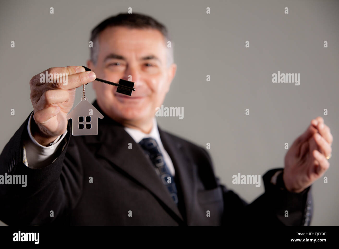 an old man reaching out a key and a little house representing real ...