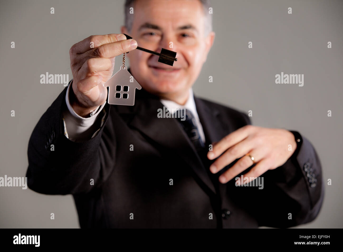 an old man reaching out a key and a little house representing real ...