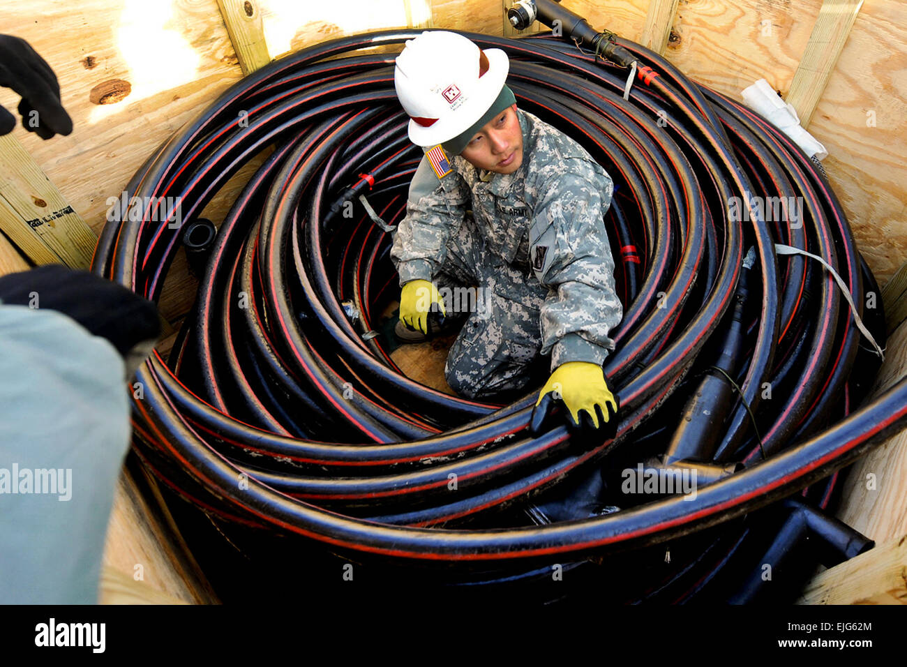 Sgt. Muy Thor inspects a large generator cable before installing it at ...