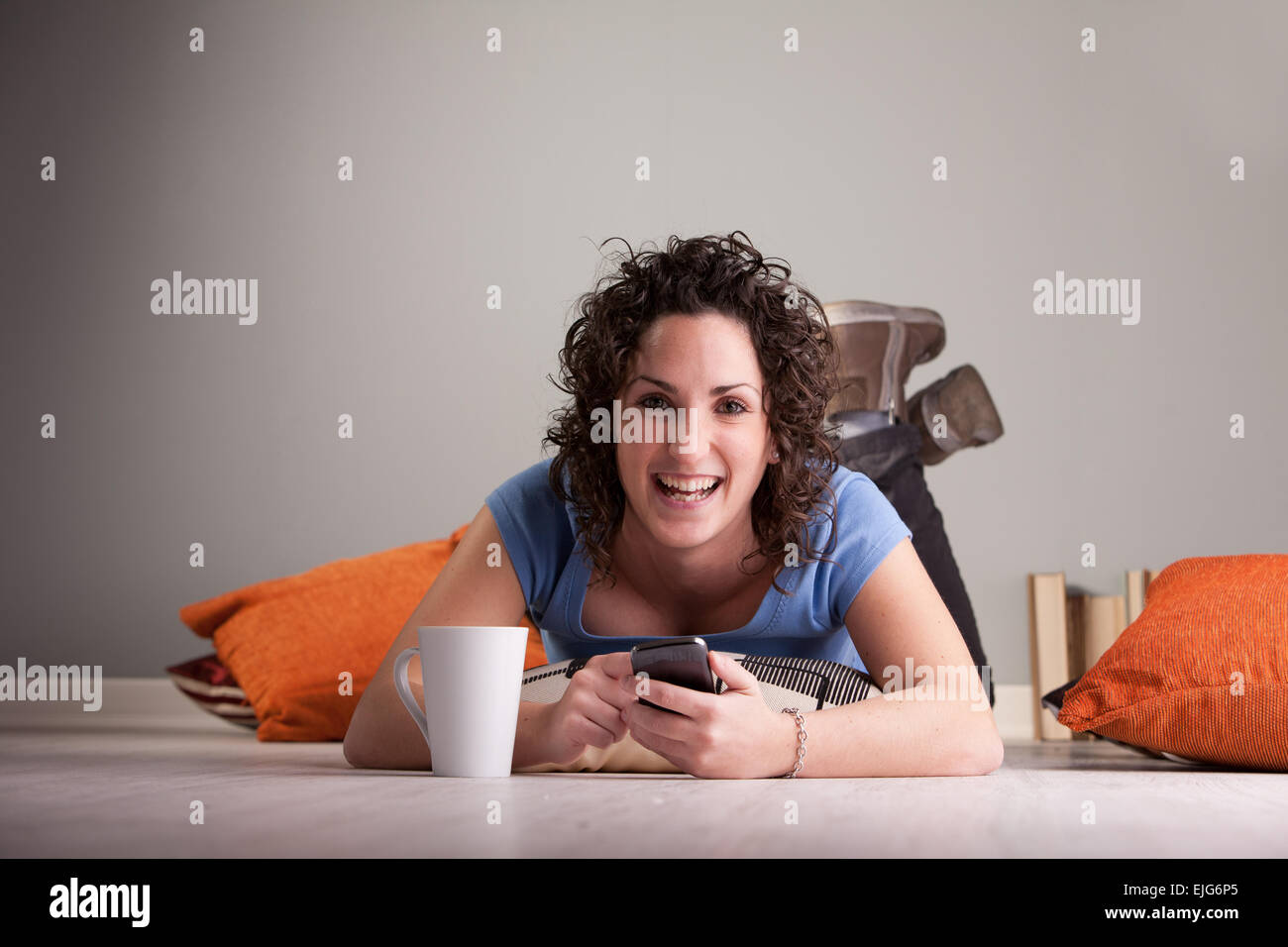 girl enjoying her mobile phone while drinking from a white mug Stock ...