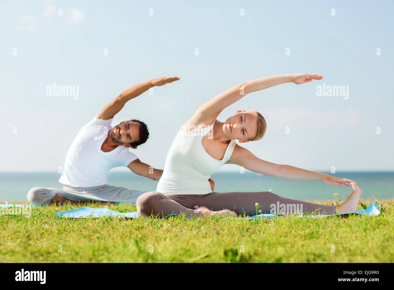 smiling couple making yoga exercises outdoors Stock Photo - Alamy