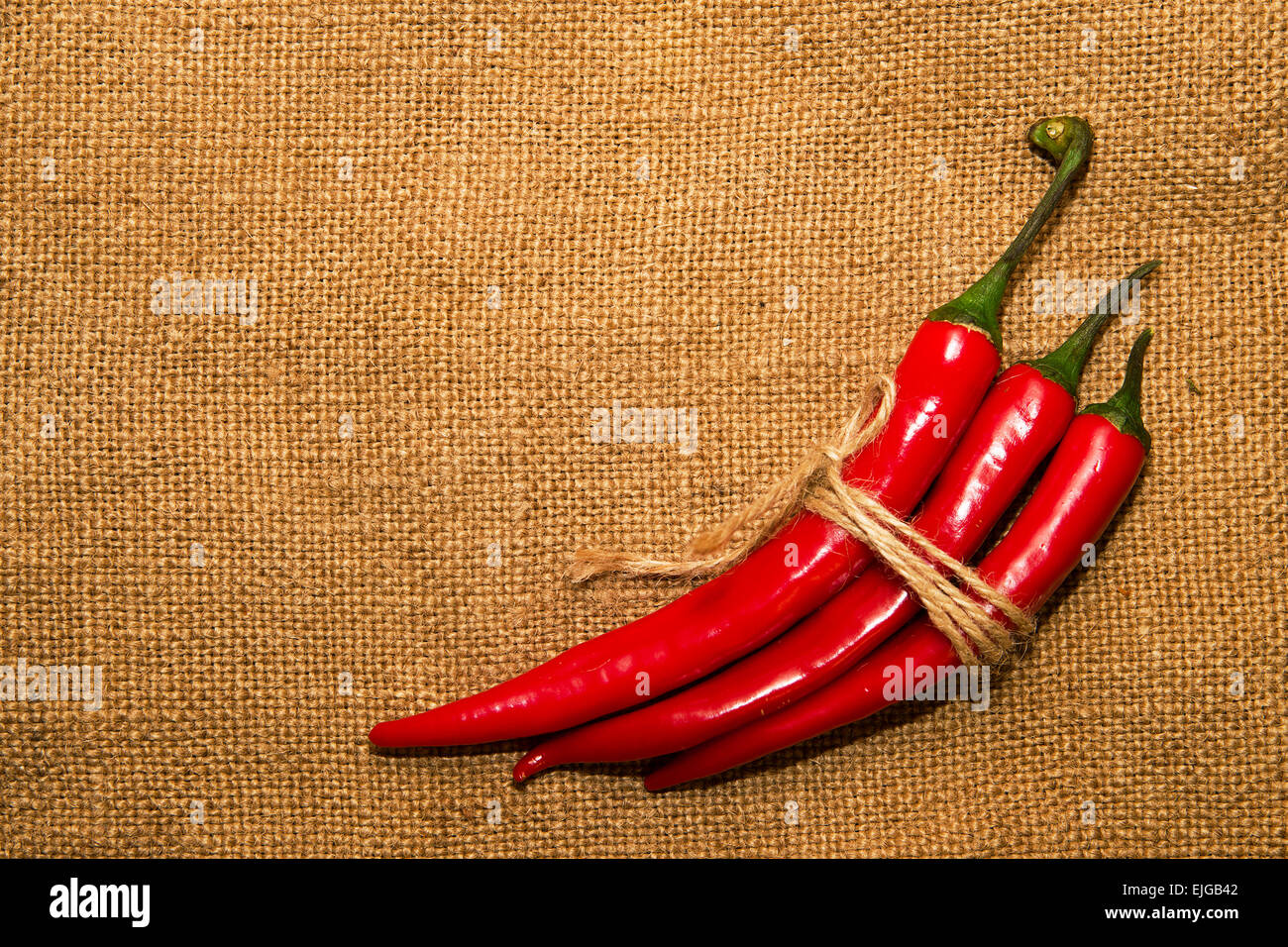 Three Chile peppers tied with a rope on old cloth Stock Photo - Alamy