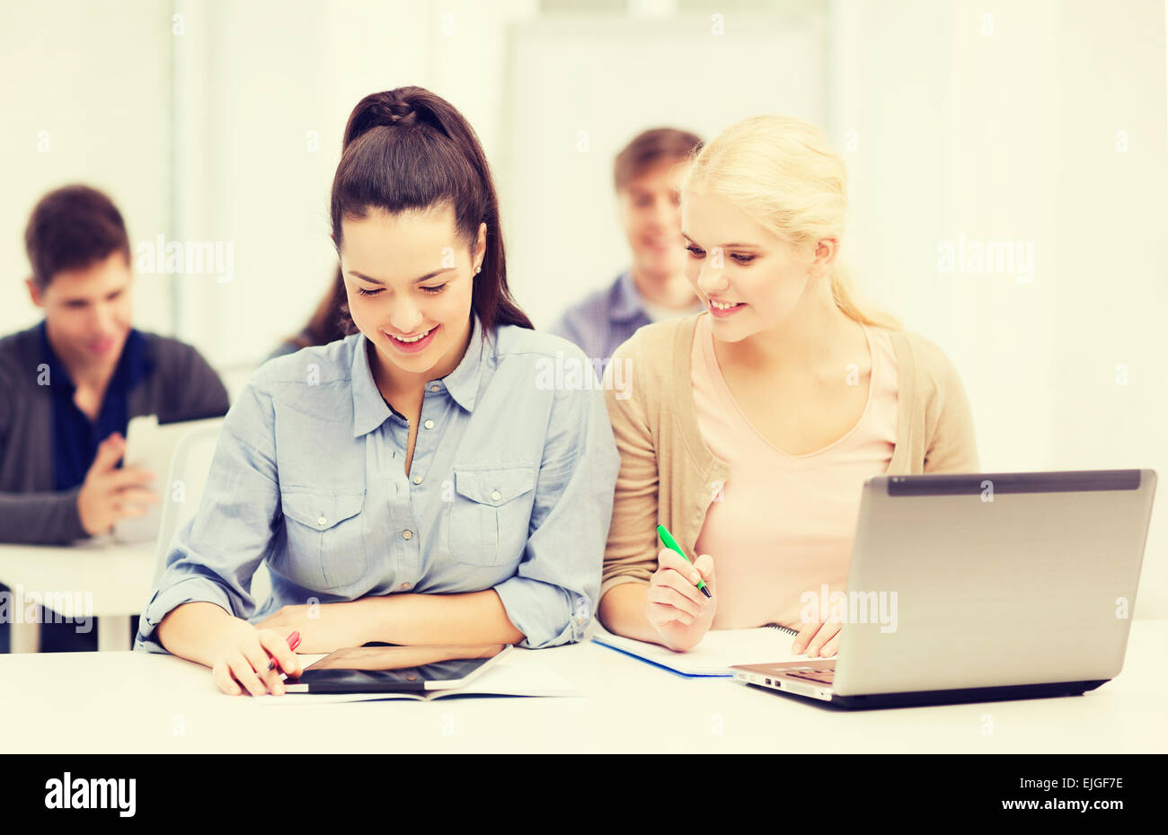 two smiling students with laptop and tablet pc Stock Photo - Alamy